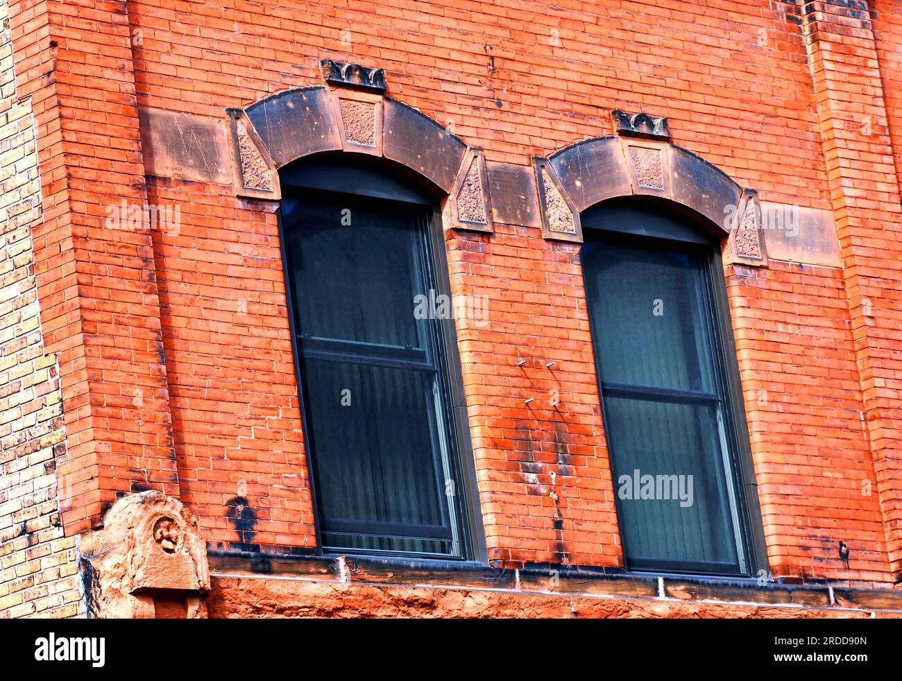Two windows are topped with red sandstone arches. Building is composed ...