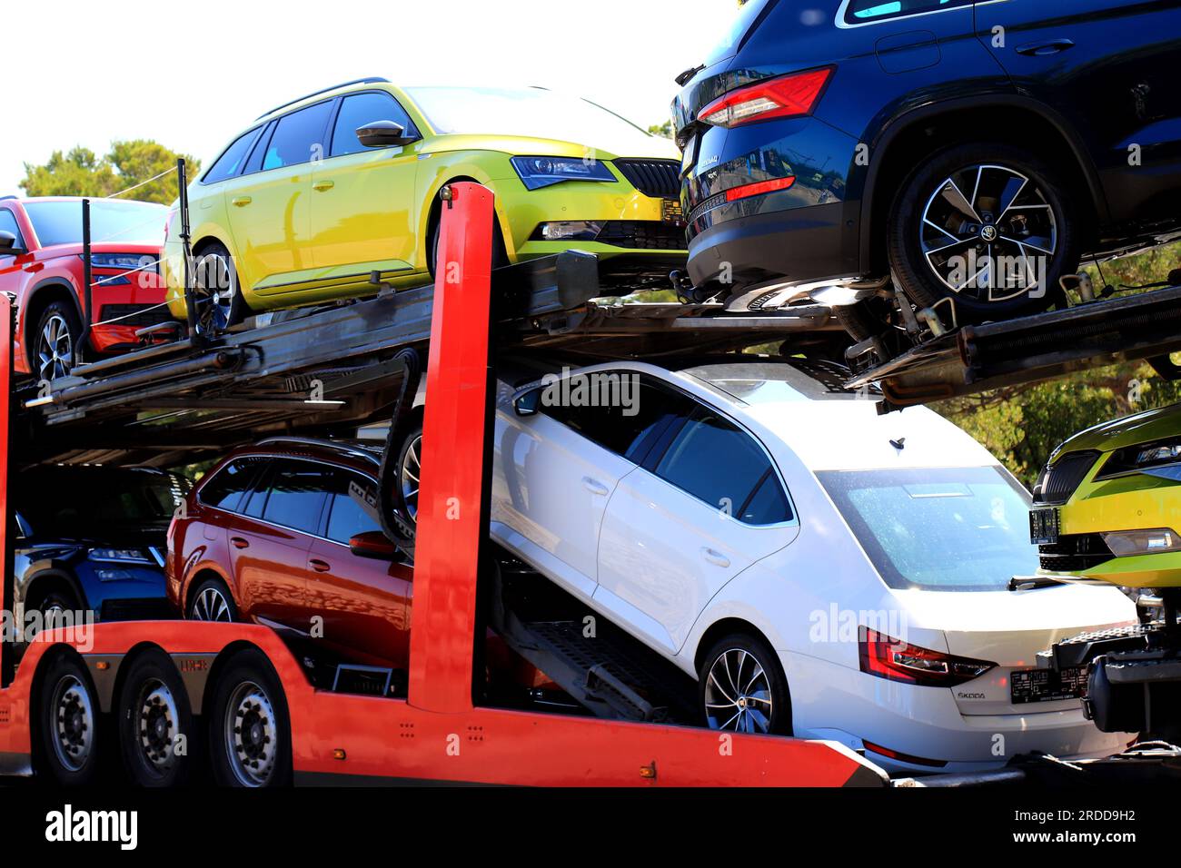 Auto transporter carries new cars of blue, yellow colors from factory ...