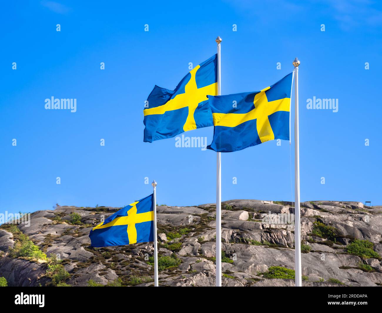 Three swedish national flags waving on the beach of Hunnebostrand ...