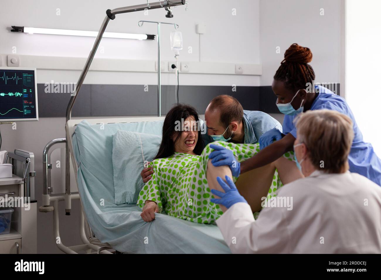 Diverse obstetrician doctor helping woman to delivery baby, being ...