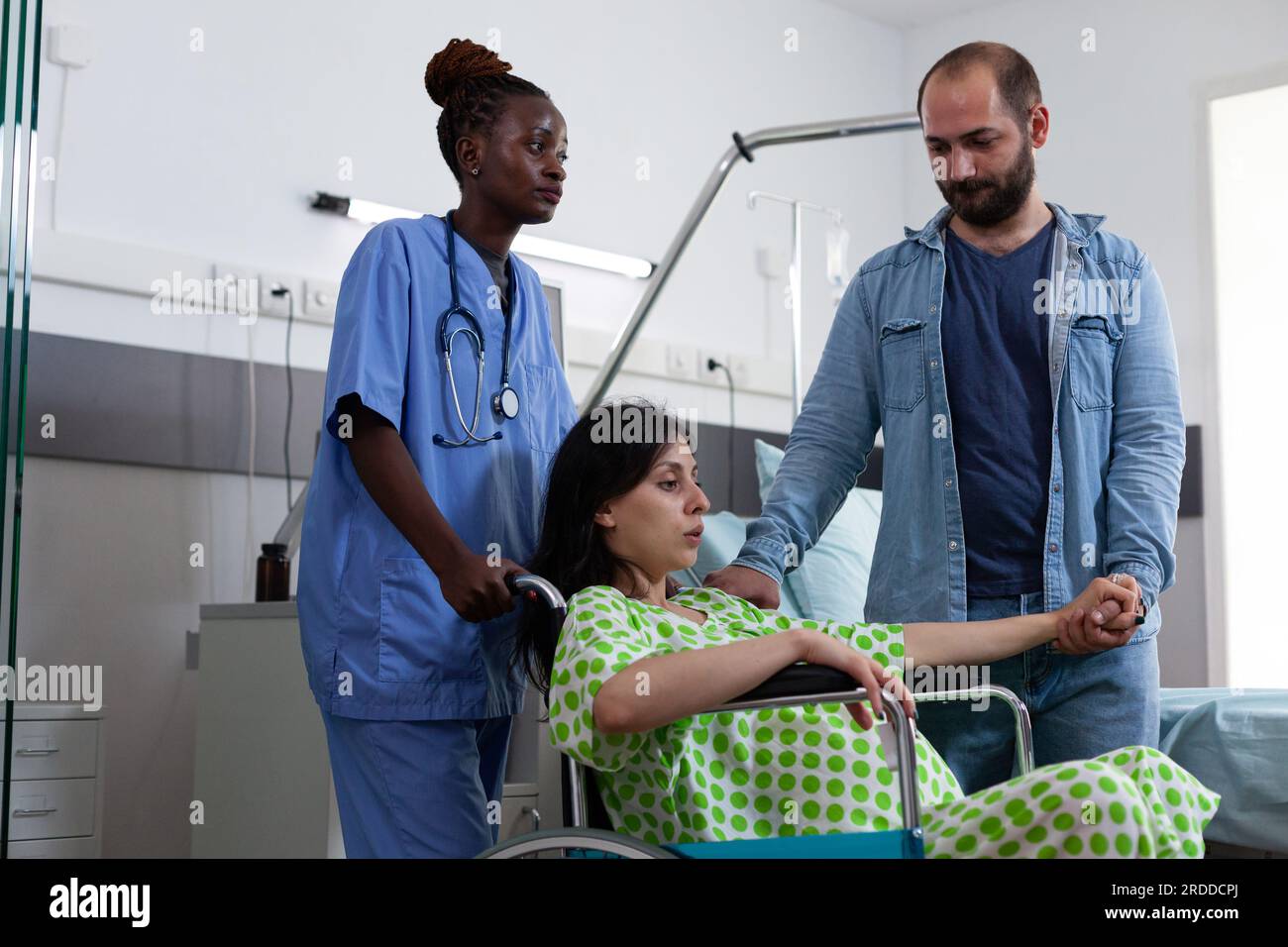 African american nurse taking pregnant woman in wheelchair to maternity ...