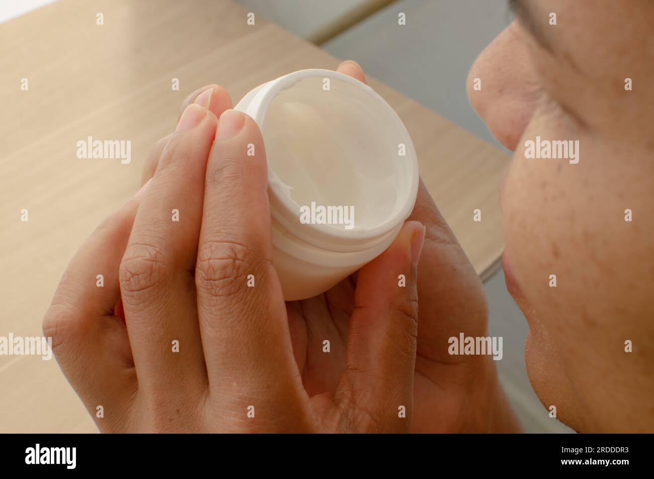 Precise gestures, female hands applying moisturizing cream to the face ...