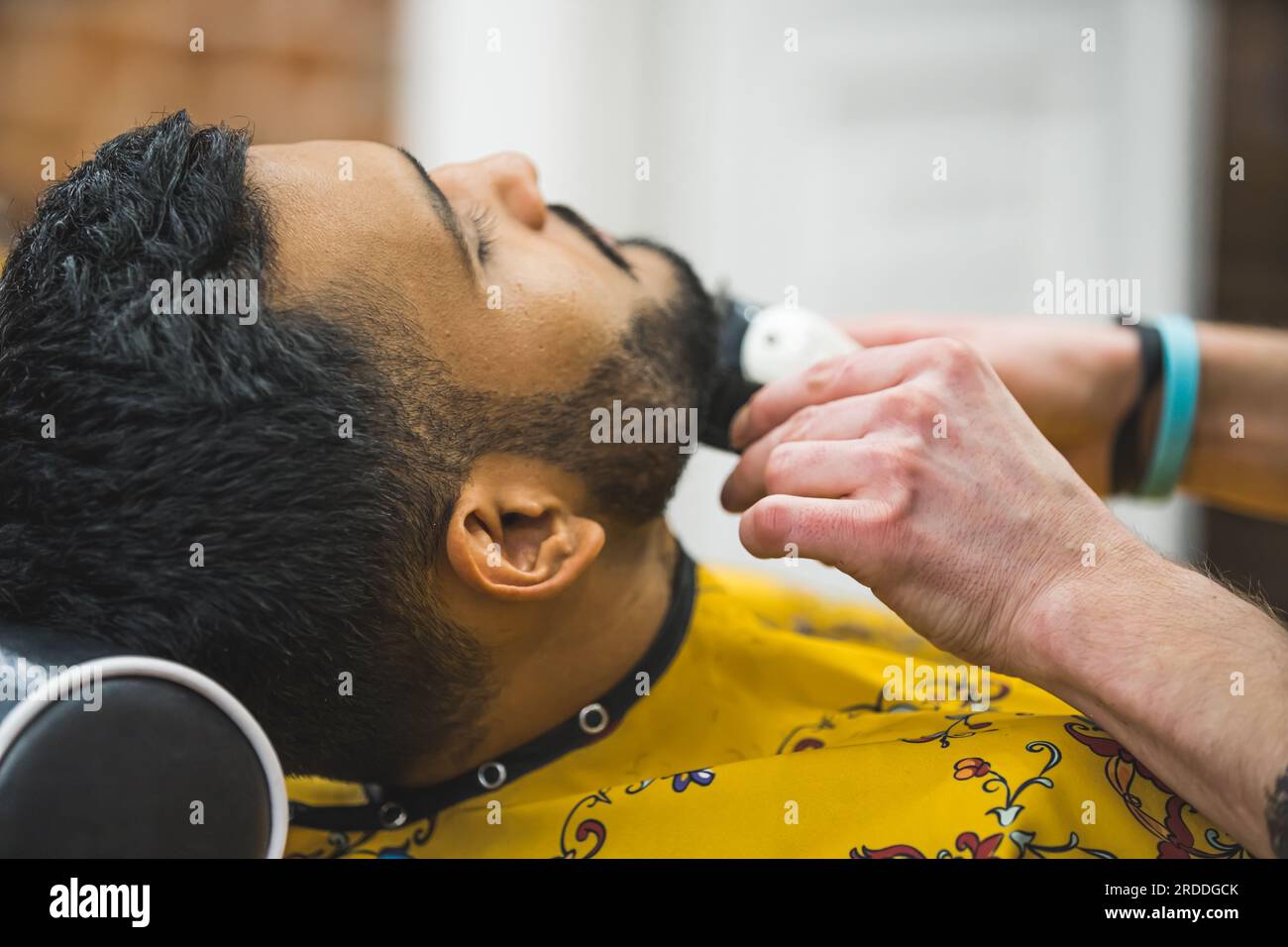 Side view face of a young man in the barbershop - Barber trimming beard ...