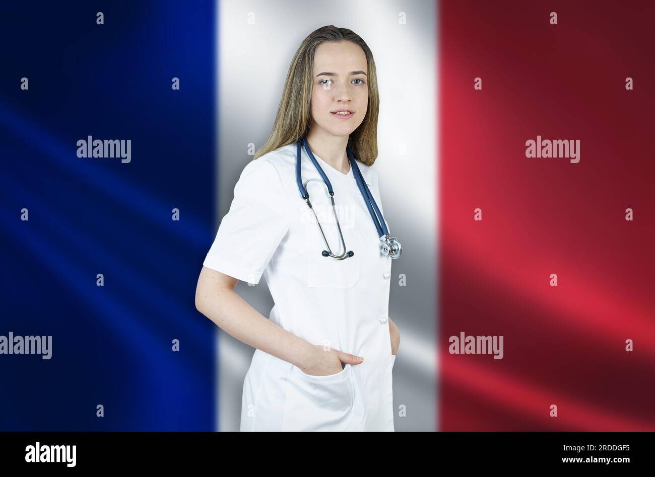 A young female doctor in a white coat and a stethoscope stands on the ...