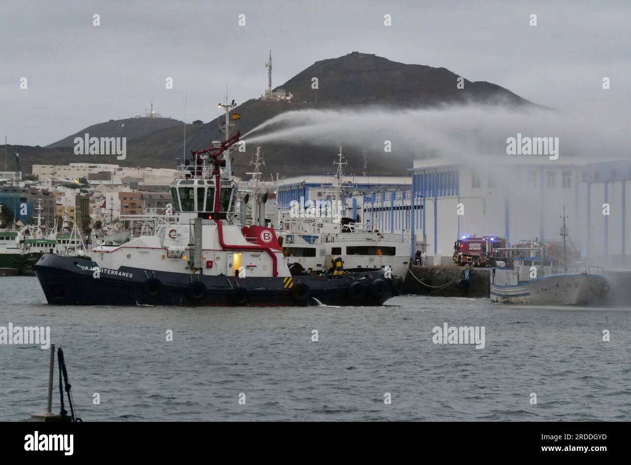 A ship works to put out a fire in a warehouse in the Port of Las Palmas ...