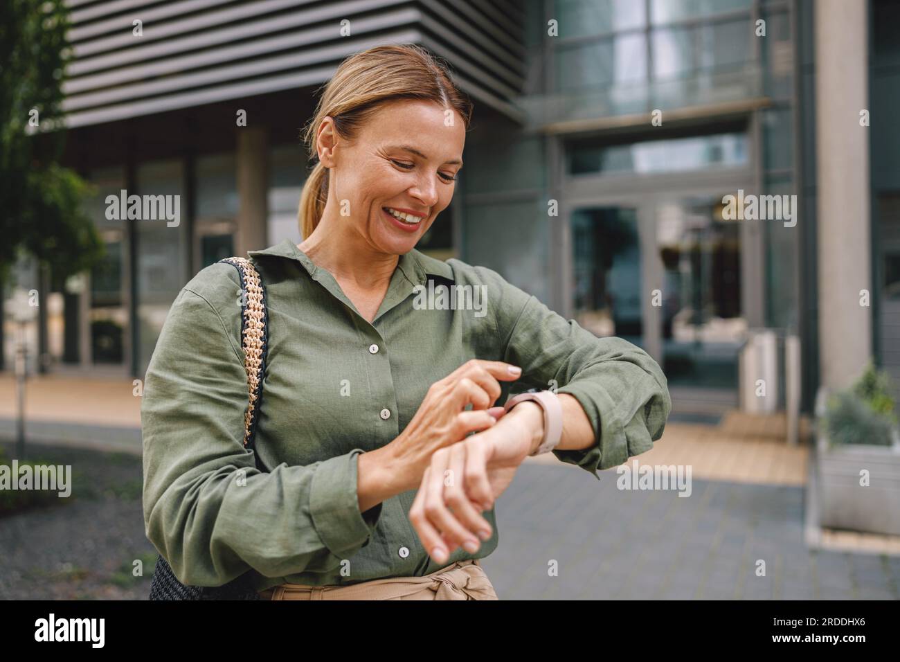 Woman freelancer looking on her wrist watch standing on modern office ...