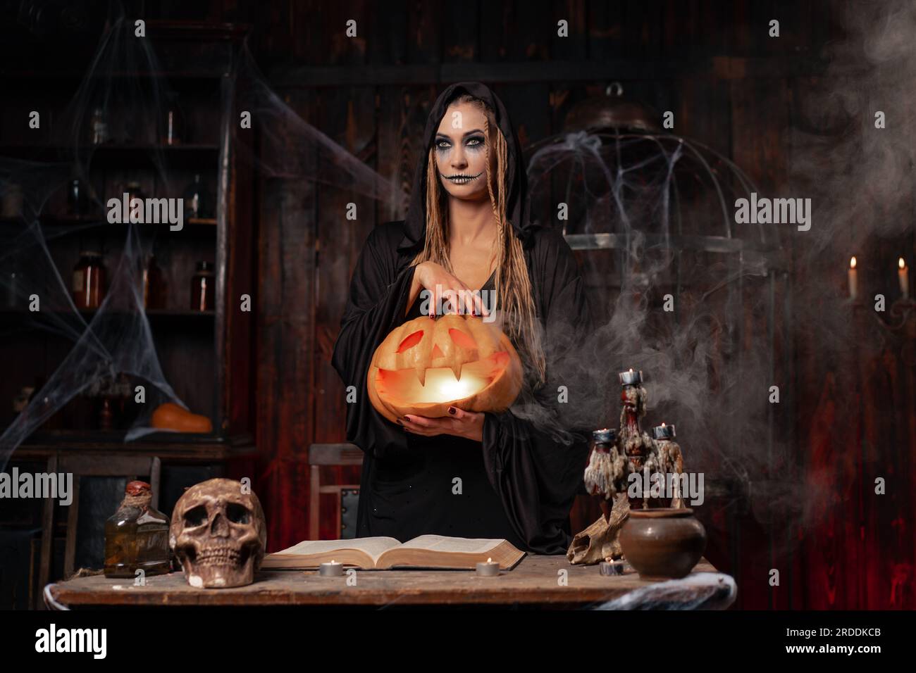 Halloween concept. Black witch holding Halloween pumpkin in hand with ...