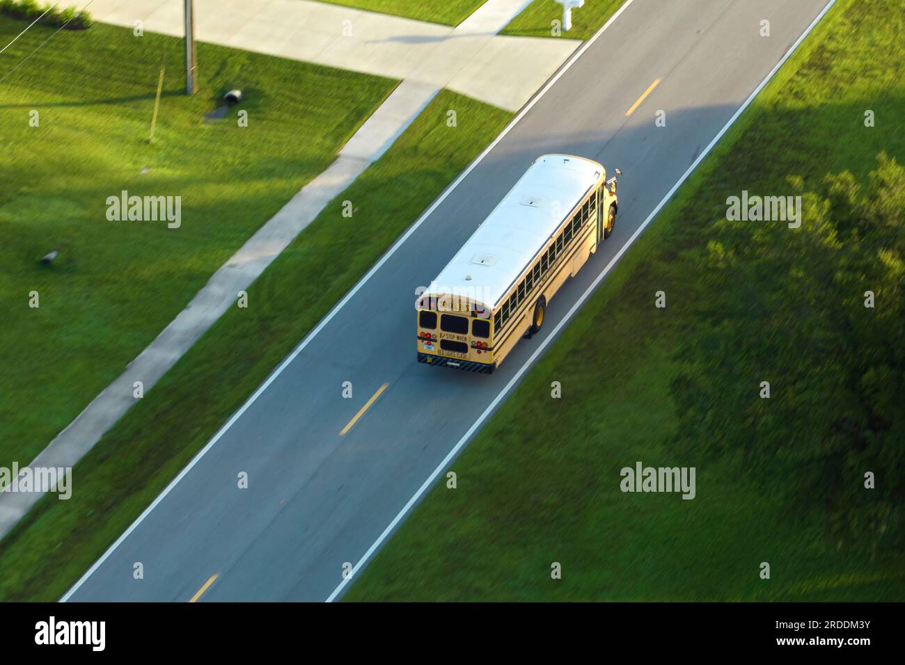 Aerial view of american yellow school bus driving on suburban street ...