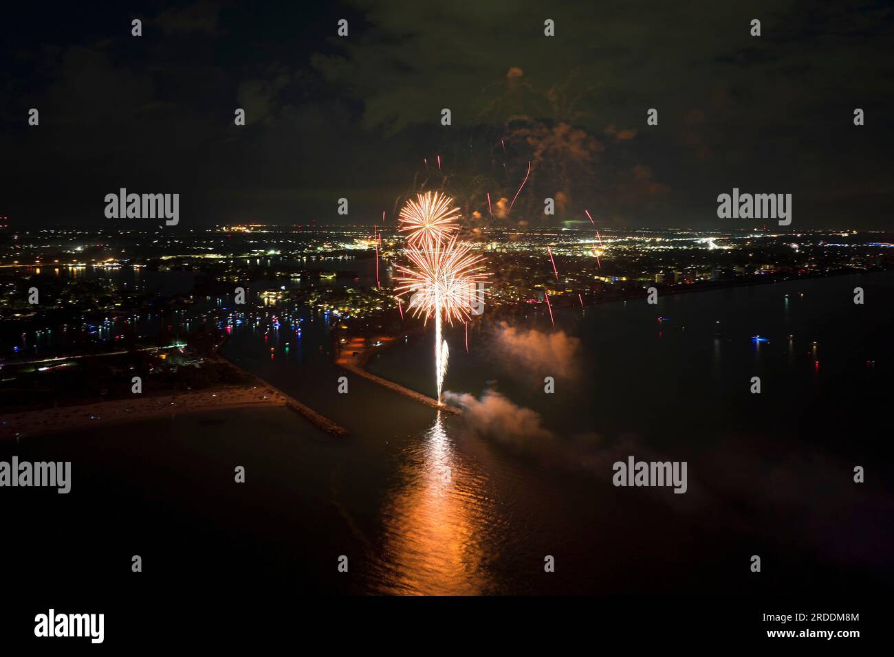 Aerial view of bright fireworks exploding with colorful lights over sea ...