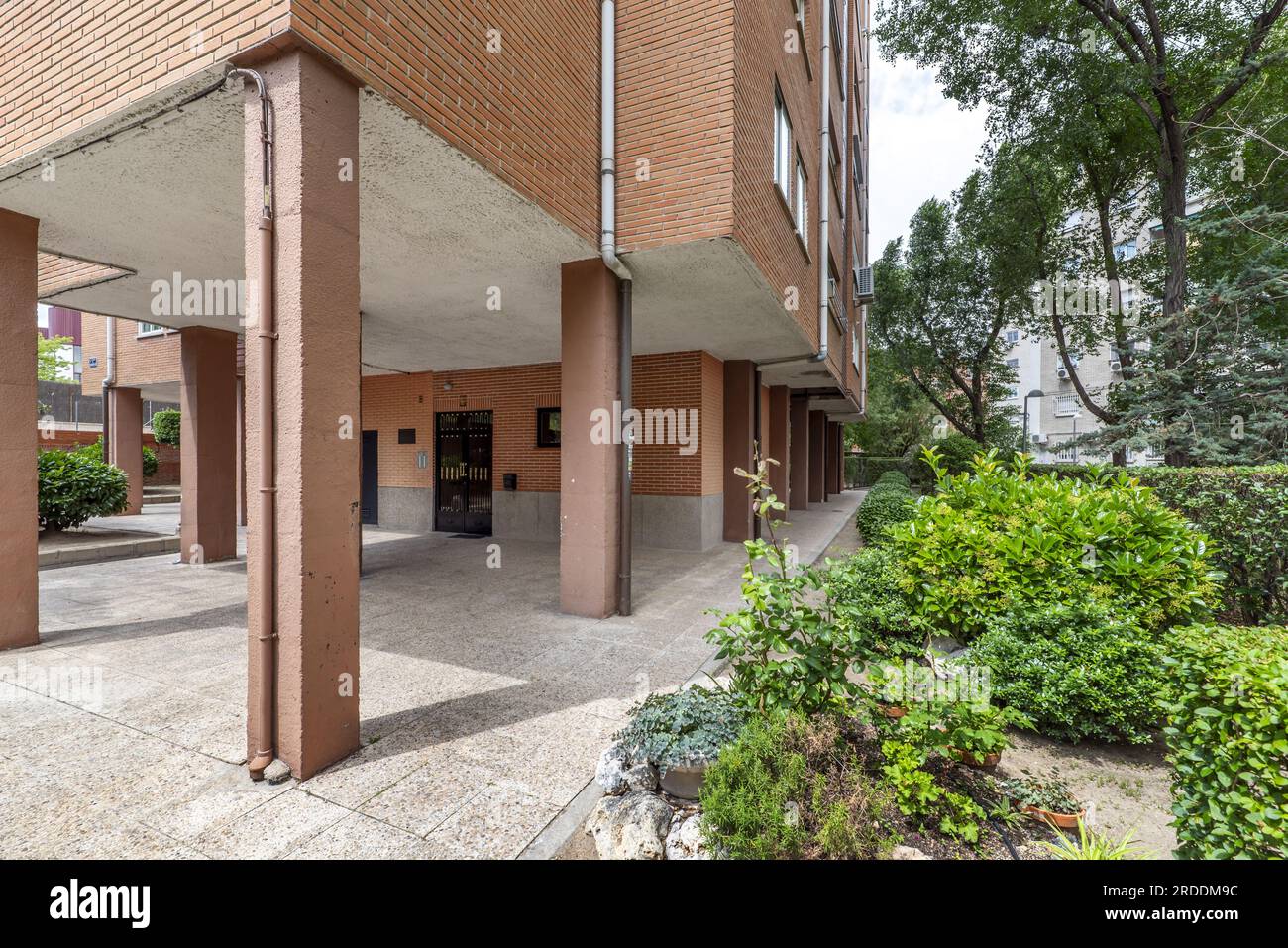 Communal areas of an urban residential building with trimmed hedges ...