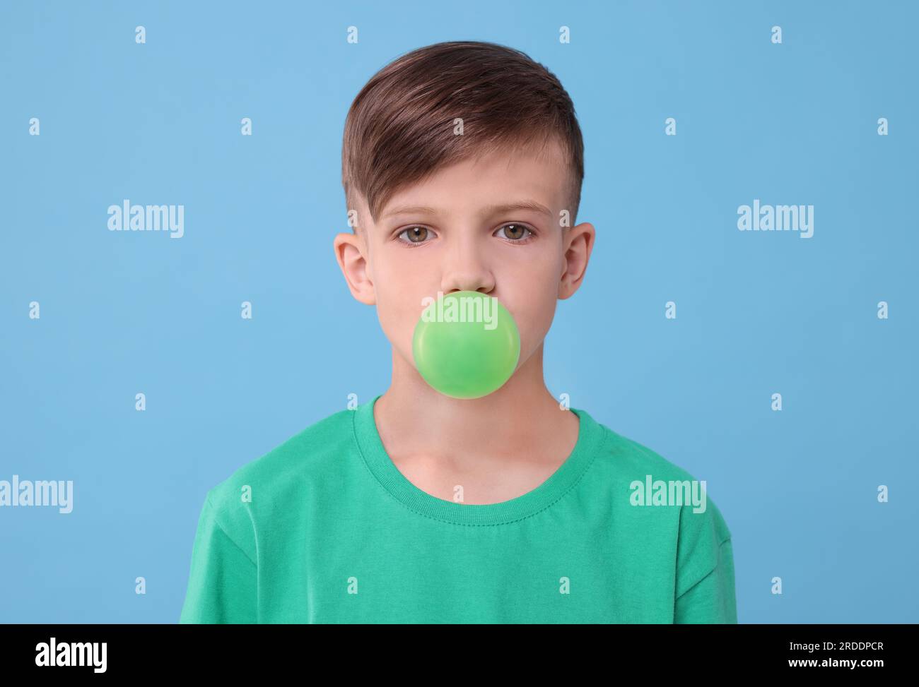 Boy blowing bubble gum on light blue background Stock Photo - Alamy
