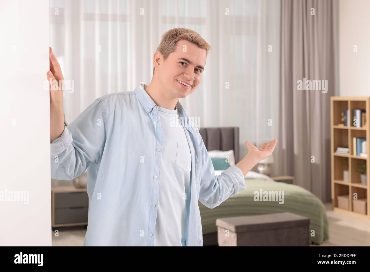 Happy man inviting to come in room Stock Photo - Alamy