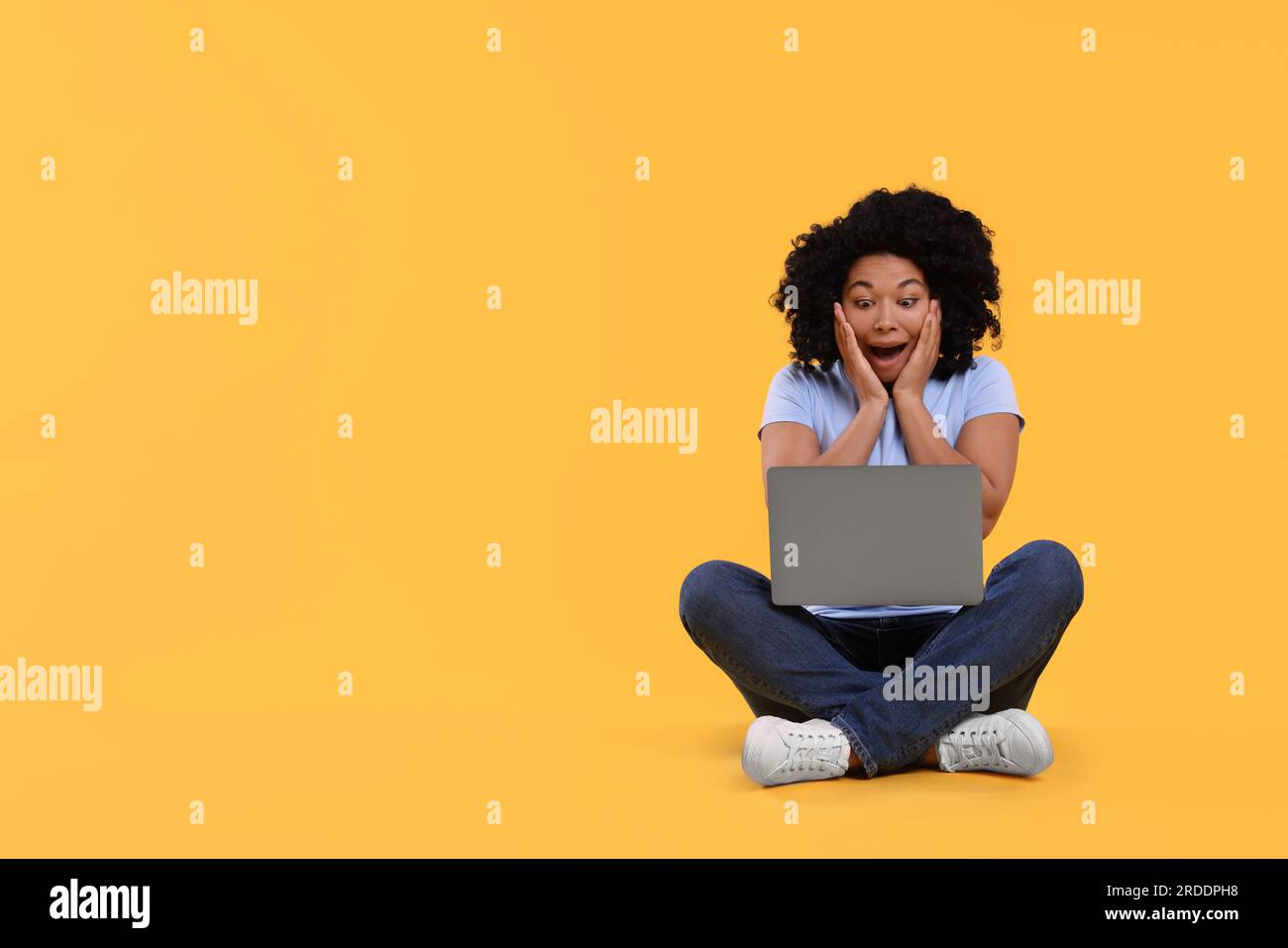 Emotional young woman with laptop on yellow background. Space for text ...