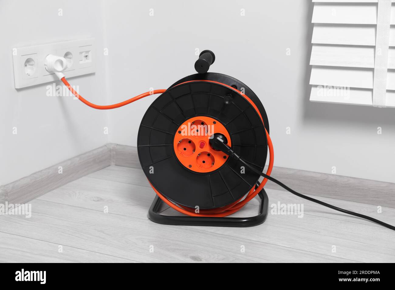 Extension cord reel plugged into socket indoors. Electrician's ...