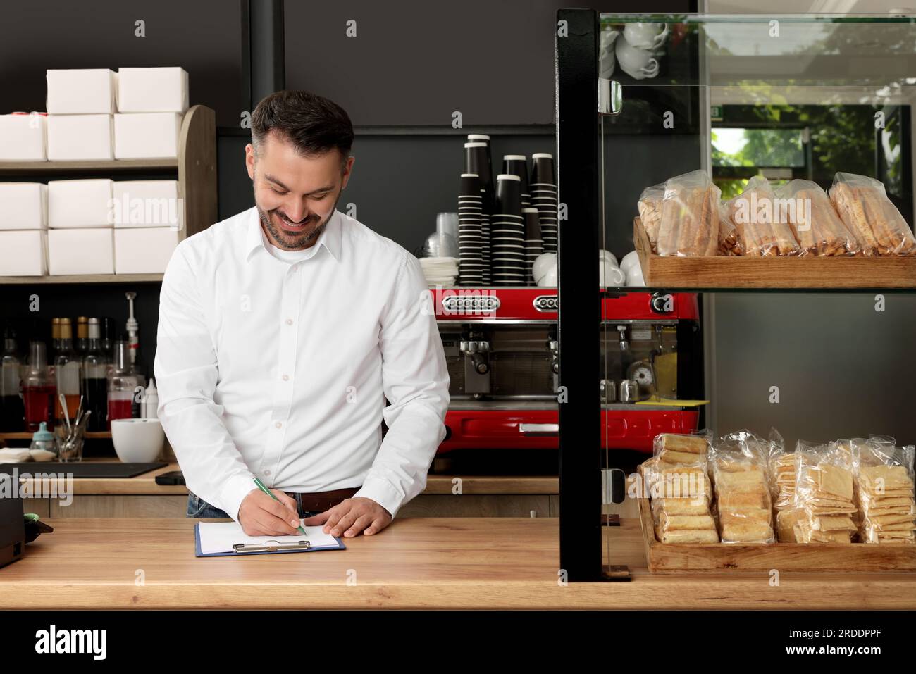 Business owner in his cafe. Man writing notes on clipboard near ...