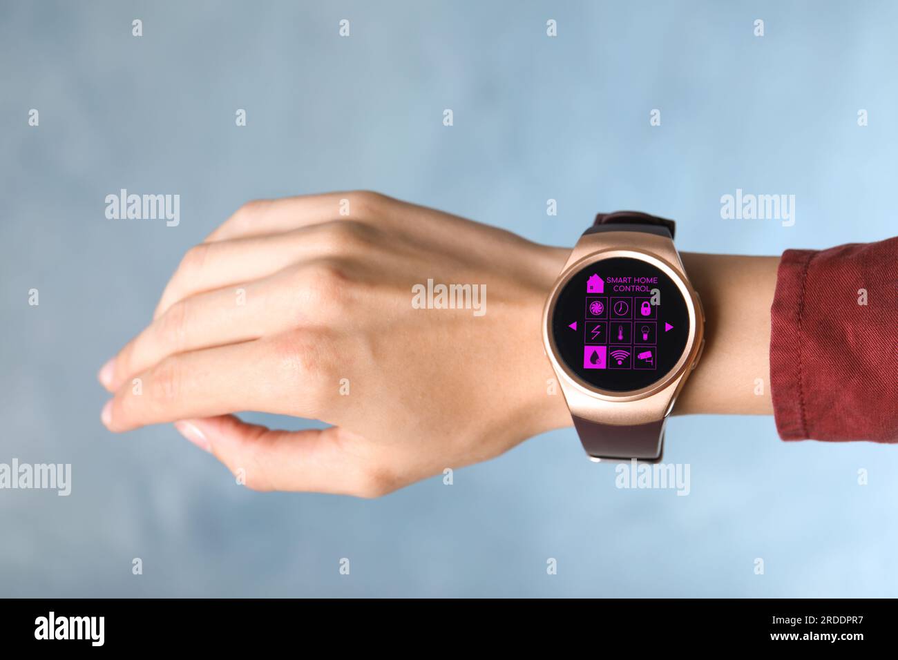 Woman wearing smartwatch with icons of smart home control app on ...