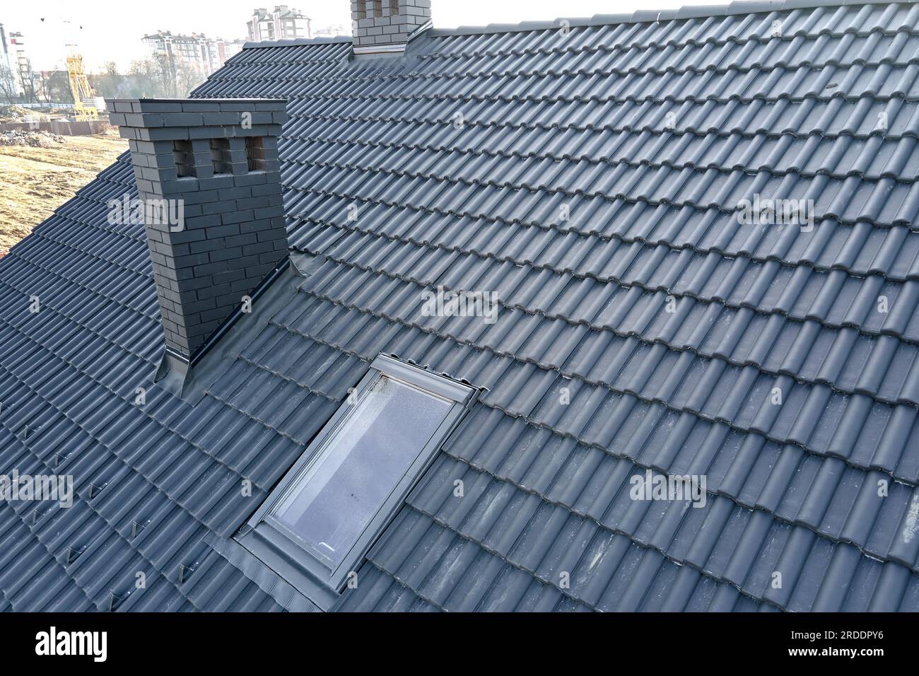 Closeup of attic window and brick chimney on house roof top covered ...