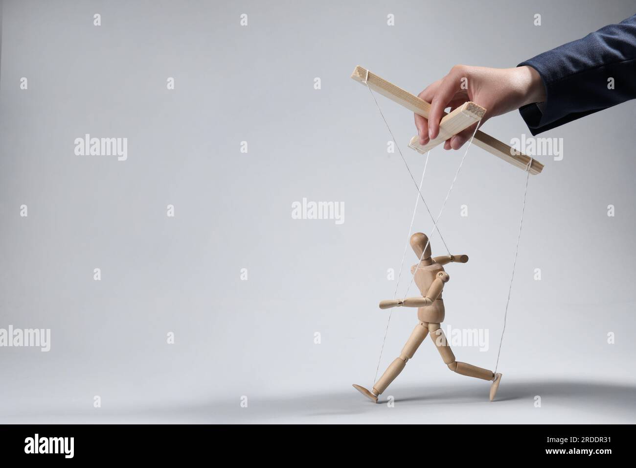 Woman pulling strings of puppet on light grey background, closeup ...
