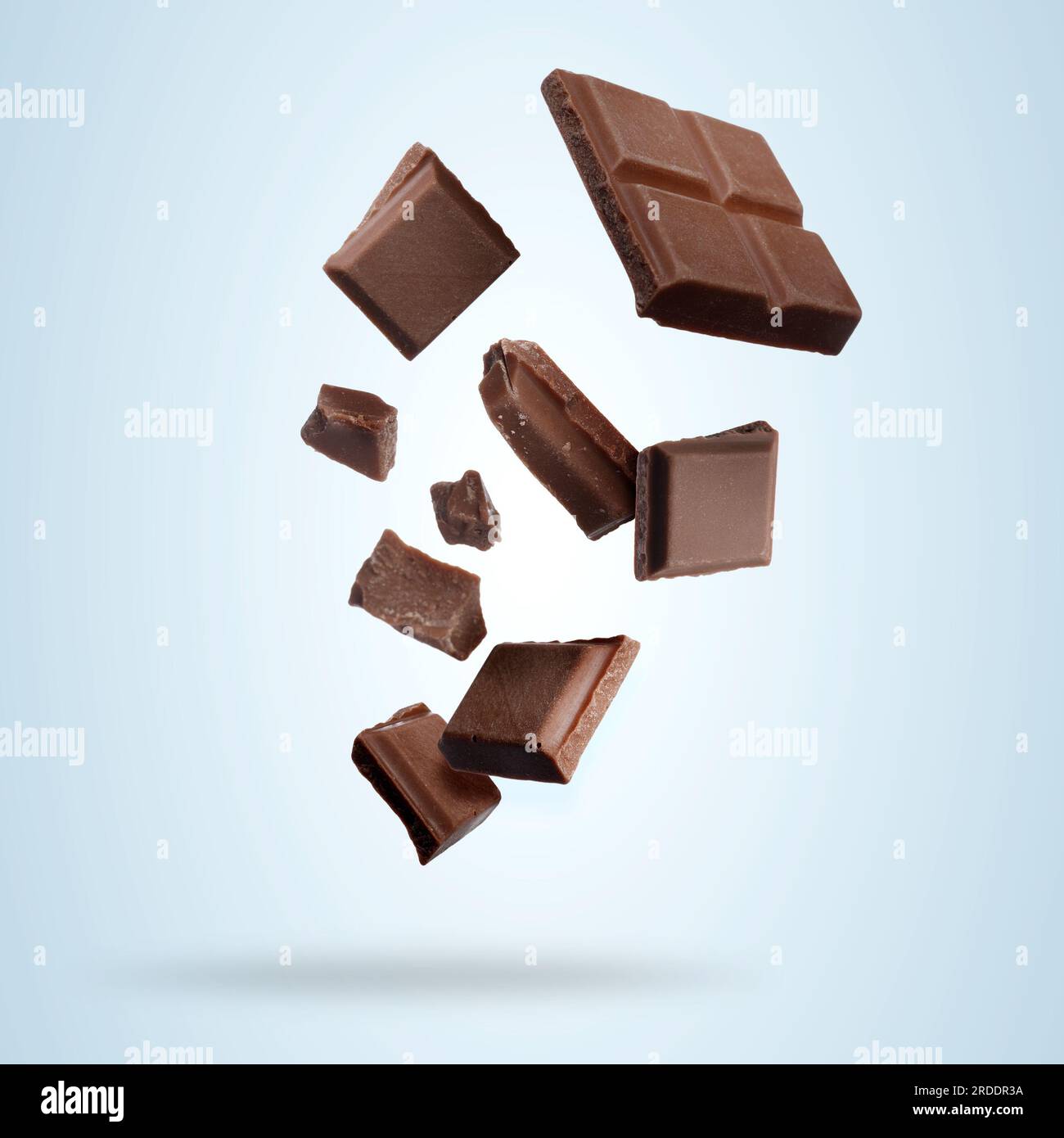 Broken chocolate bar pieces falling on light blue background Stock ...