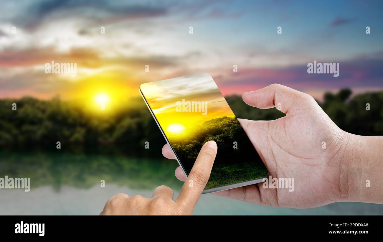 Man taking a picture with his mobile phone with a sunset scene ...