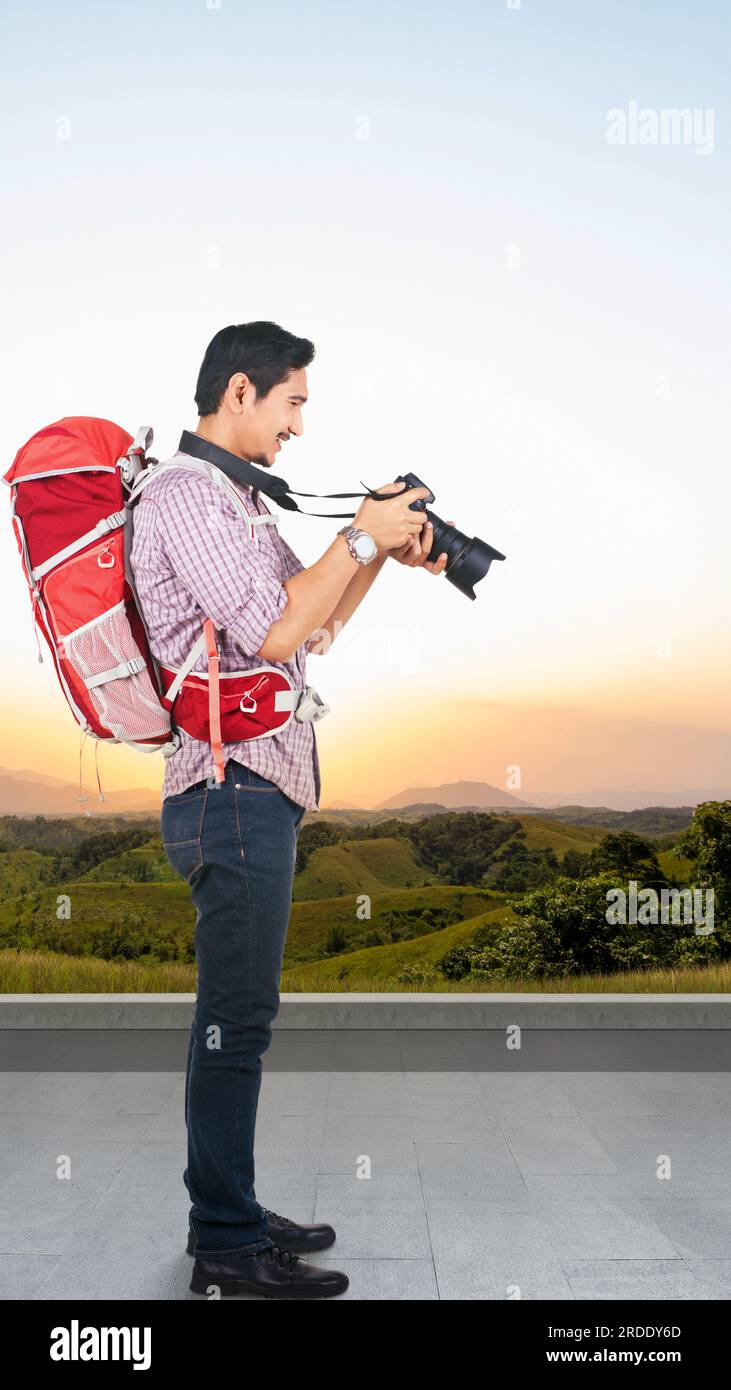 Asian man with a backpack holding the camera. World Photography Day ...