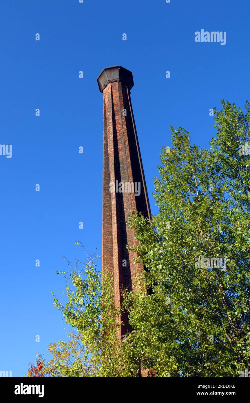 Framed by blue sky, a tall, brick smoke stack represents industry in ...