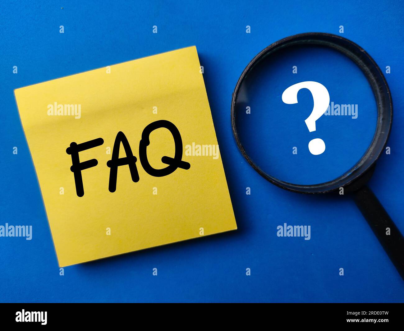 Magnifying glass and sticker note with the word FAQ on a blue ...