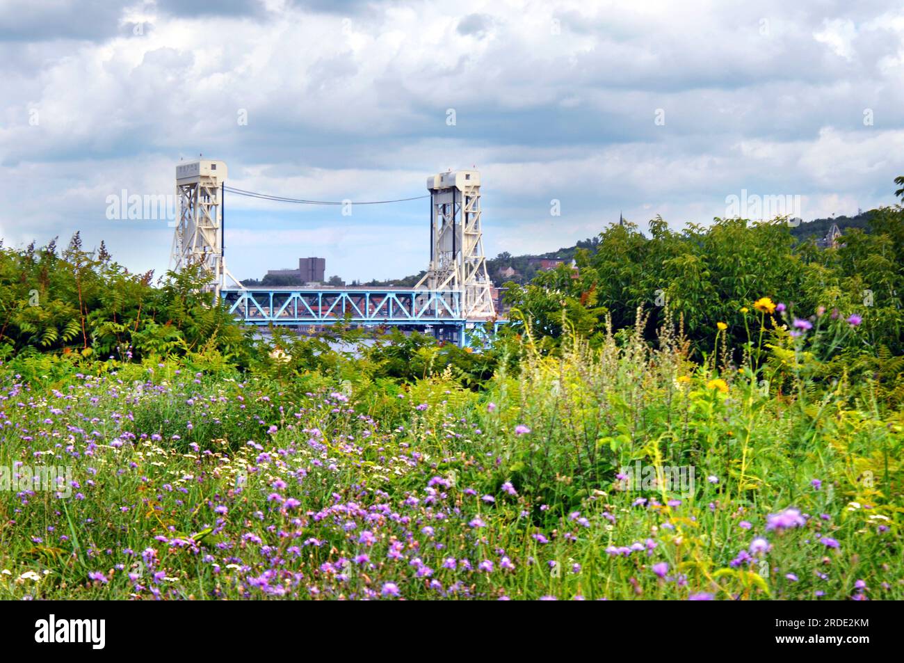 Portage Lake Lift Bridge is framed by summer flowers and cloudy sky ...