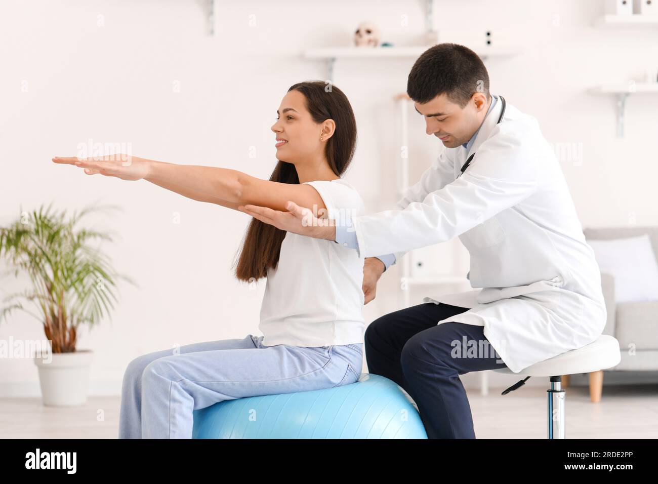 Male doctor checking posture of young woman in clinic Stock Photo - Alamy