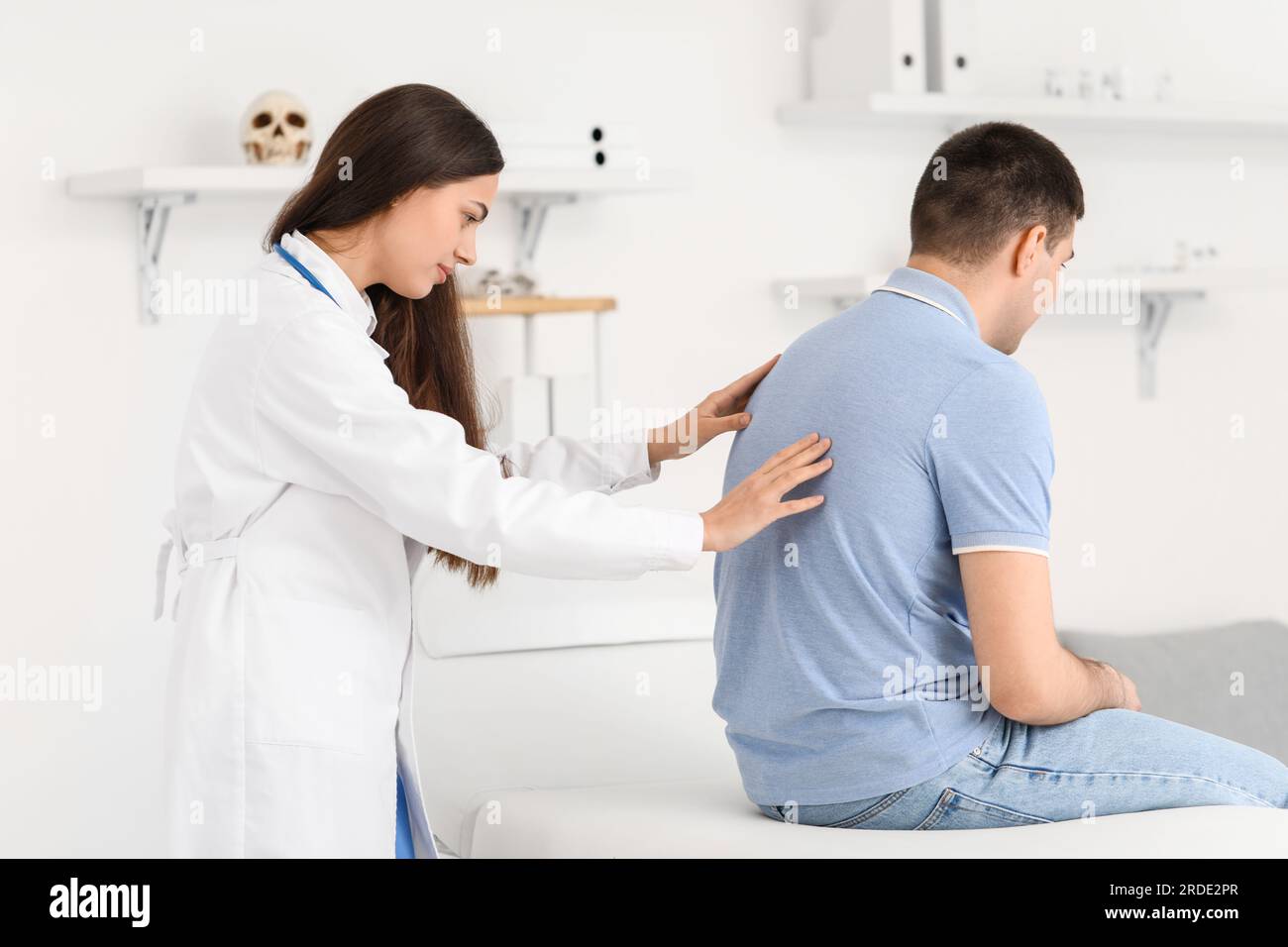 Female doctor checking posture of young man in clinic Stock Photo - Alamy