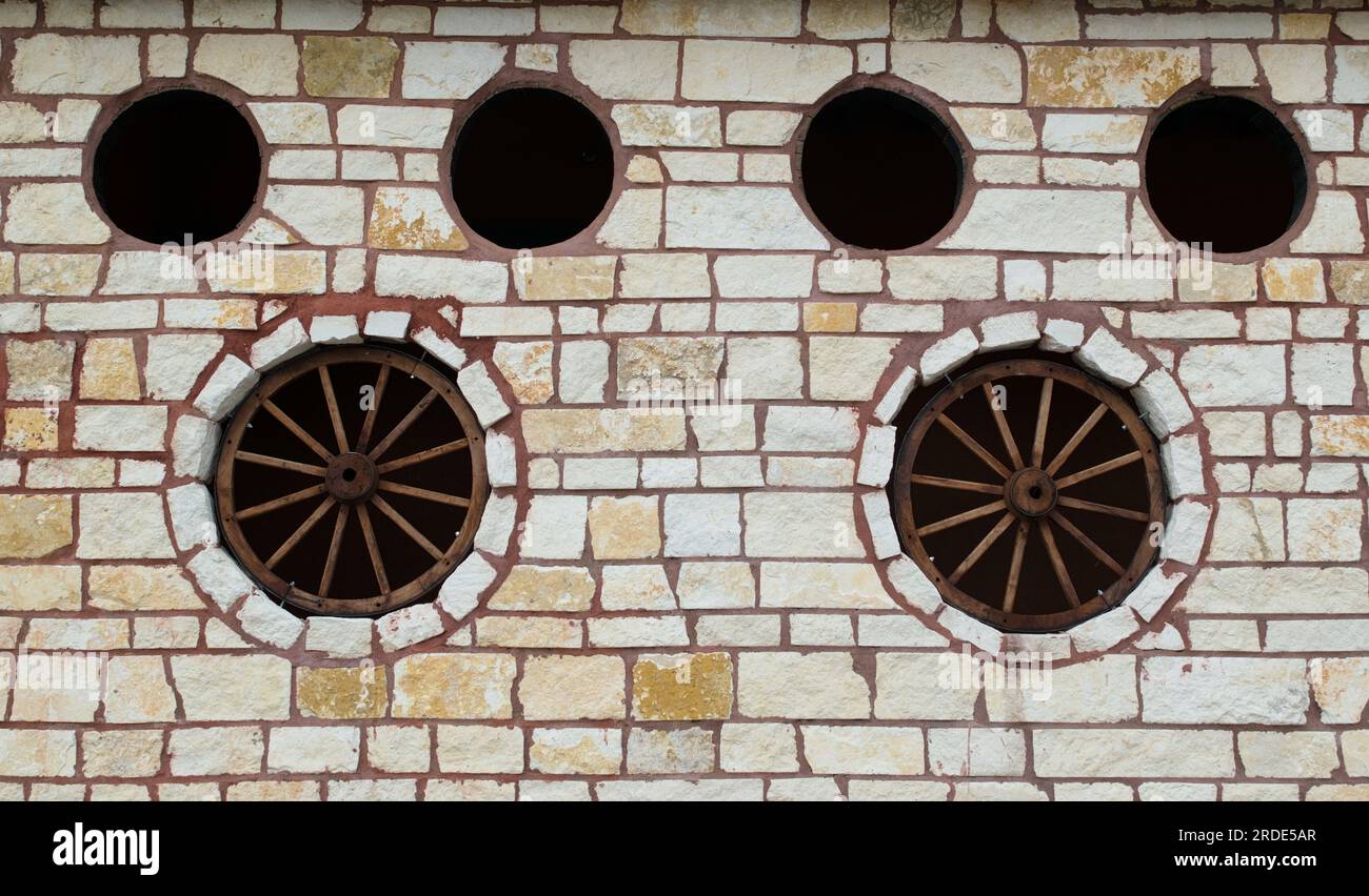 Rustic feature stone wall with wagon wheels and round portals inside ...