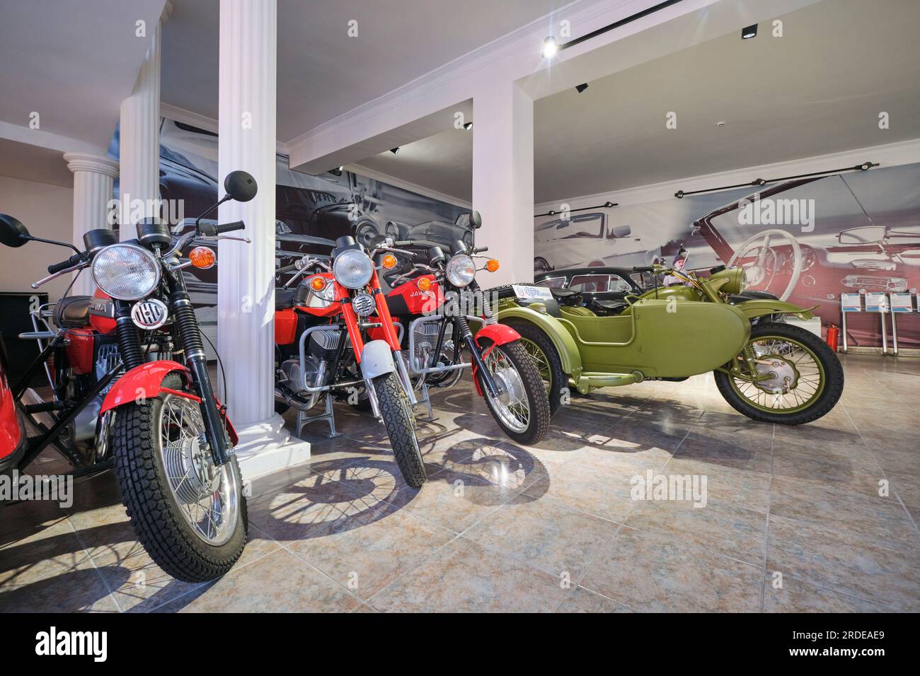 A small collection of old motorcycles, some in red and a vintage green ...