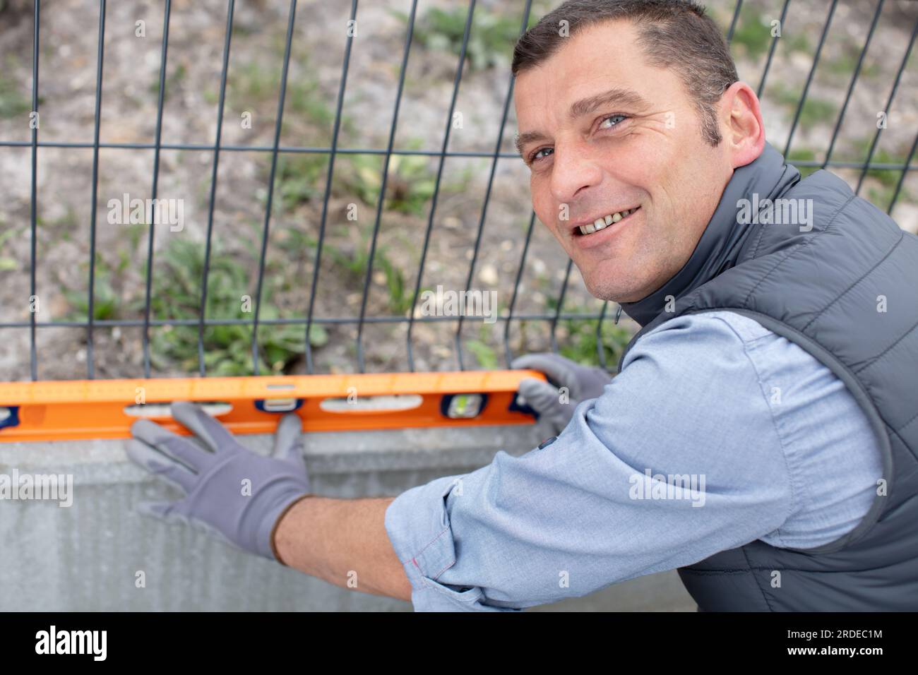 fence construction - worker check the level of metal post Stock Photo ...