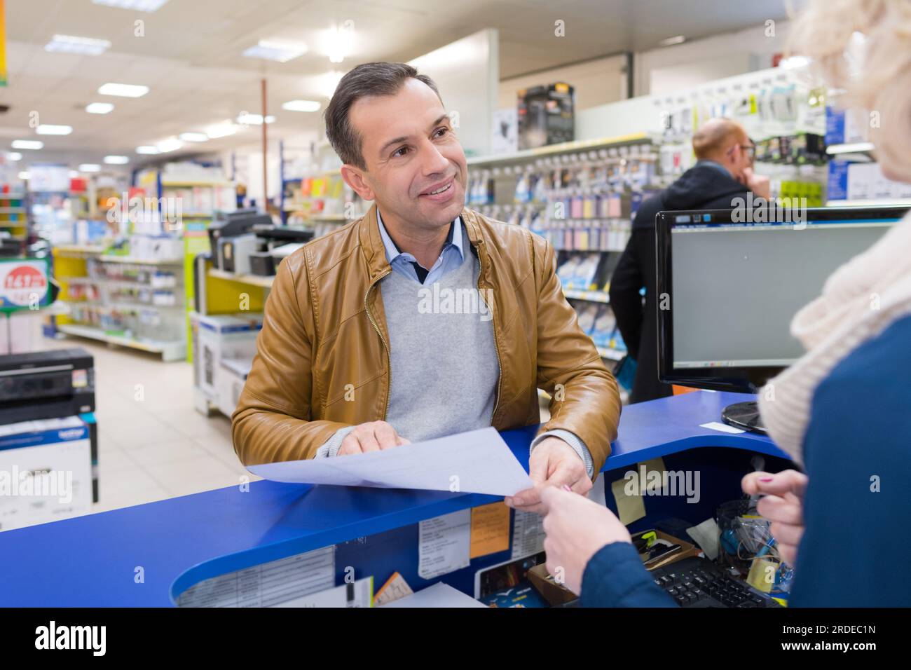 man making enquiry at shop counter Stock Photo - Alamy