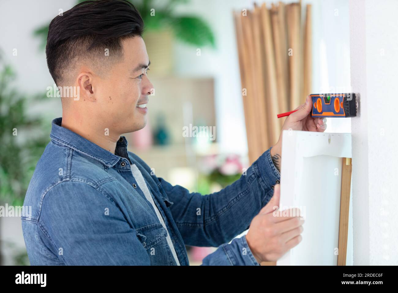 young man using spirit level on white wall at home Stock Photo - Alamy