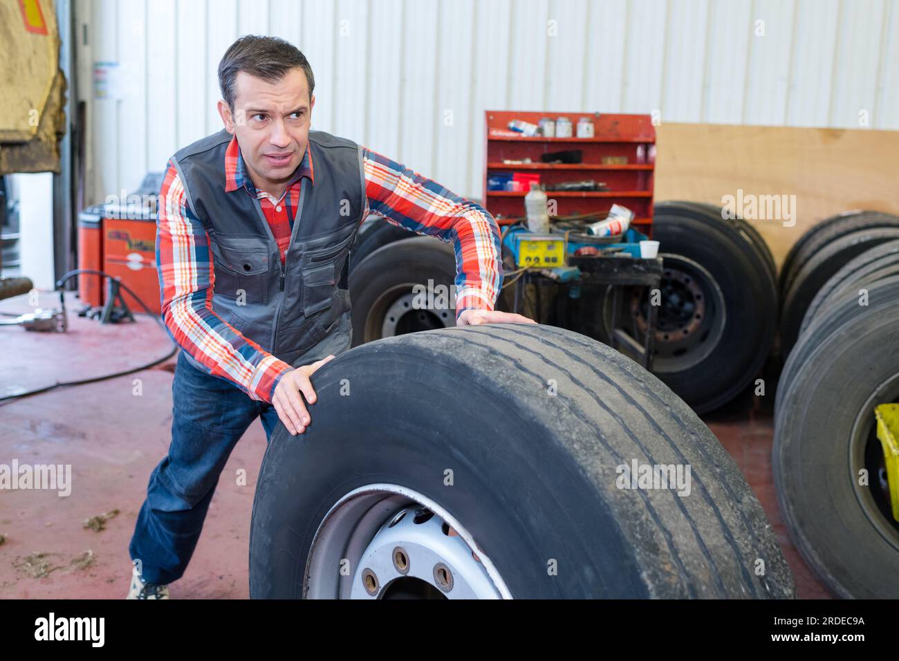 mechanic pushing heavy lorry wheel Stock Photo - Alamy
