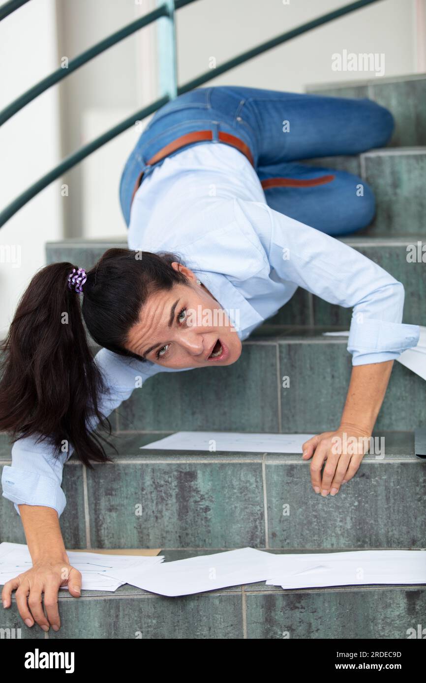 young woman falling down a staircase and dropping paperwork Stock Photo ...
