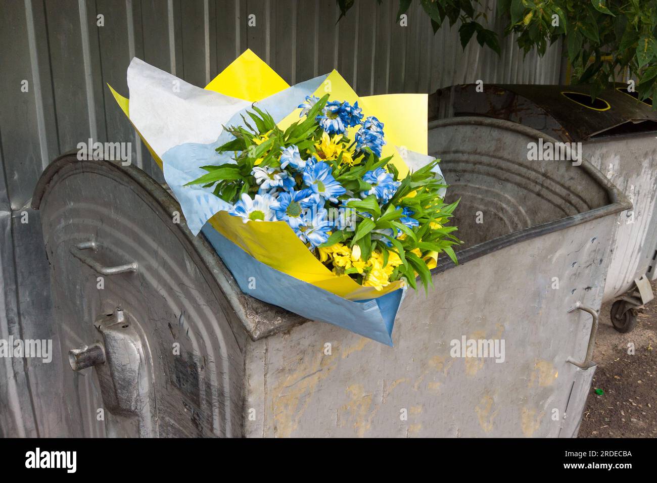 A flower bouquet thrown in trash container. Flowers bouquet at garbage ...