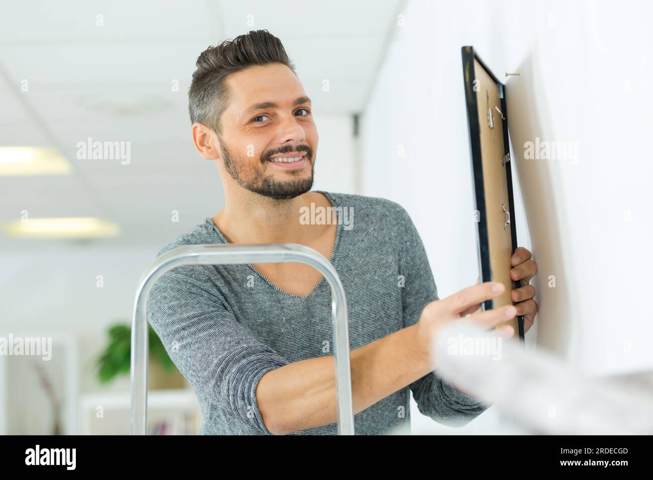male worker for hanging picture frame on wall at home Stock Photo - Alamy