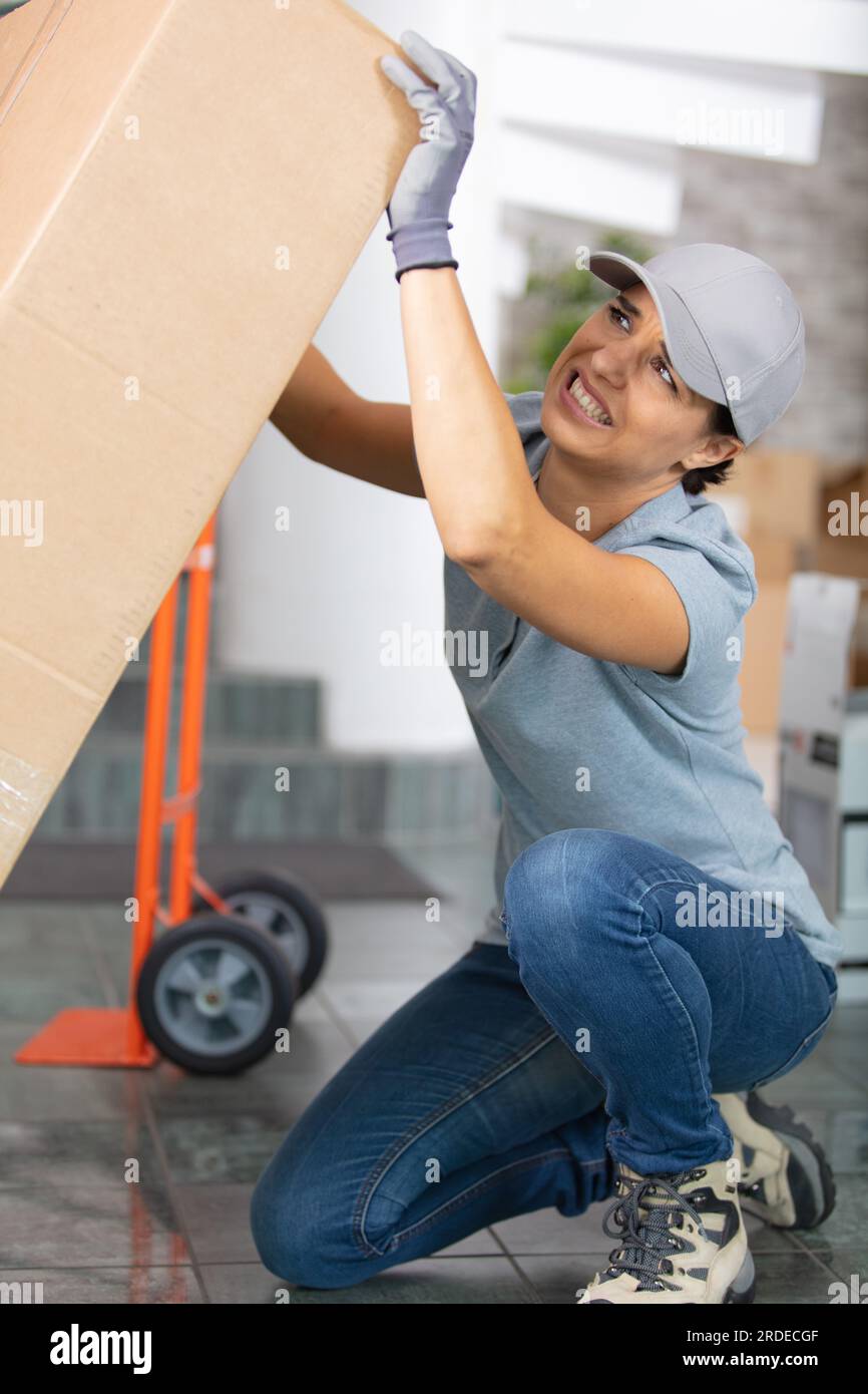 woman strainging to lift heavy box Stock Photo - Alamy