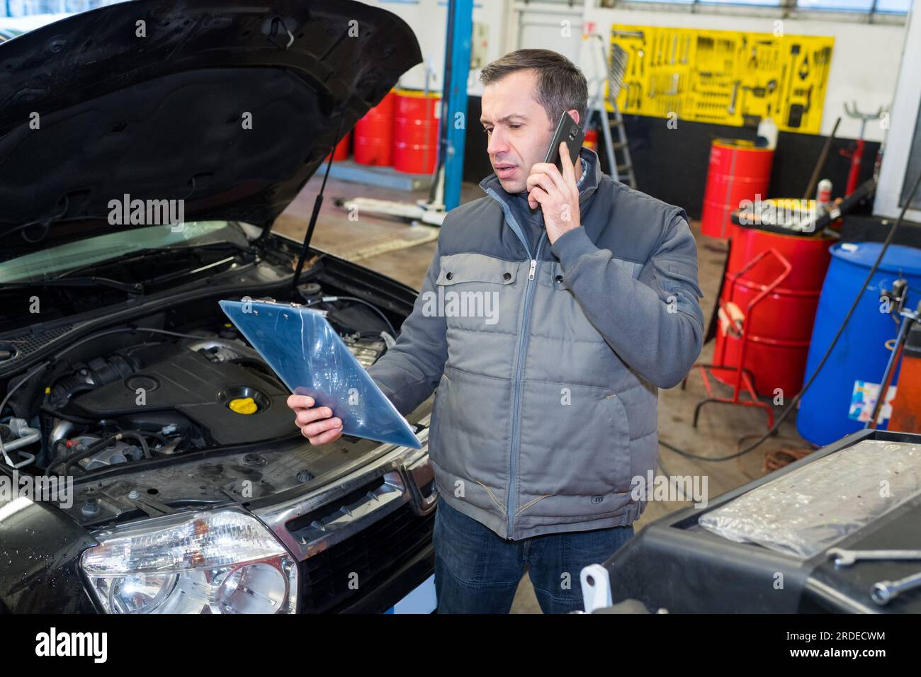 auto-mechanic man with clipboard on the phone Stock Photo - Alamy