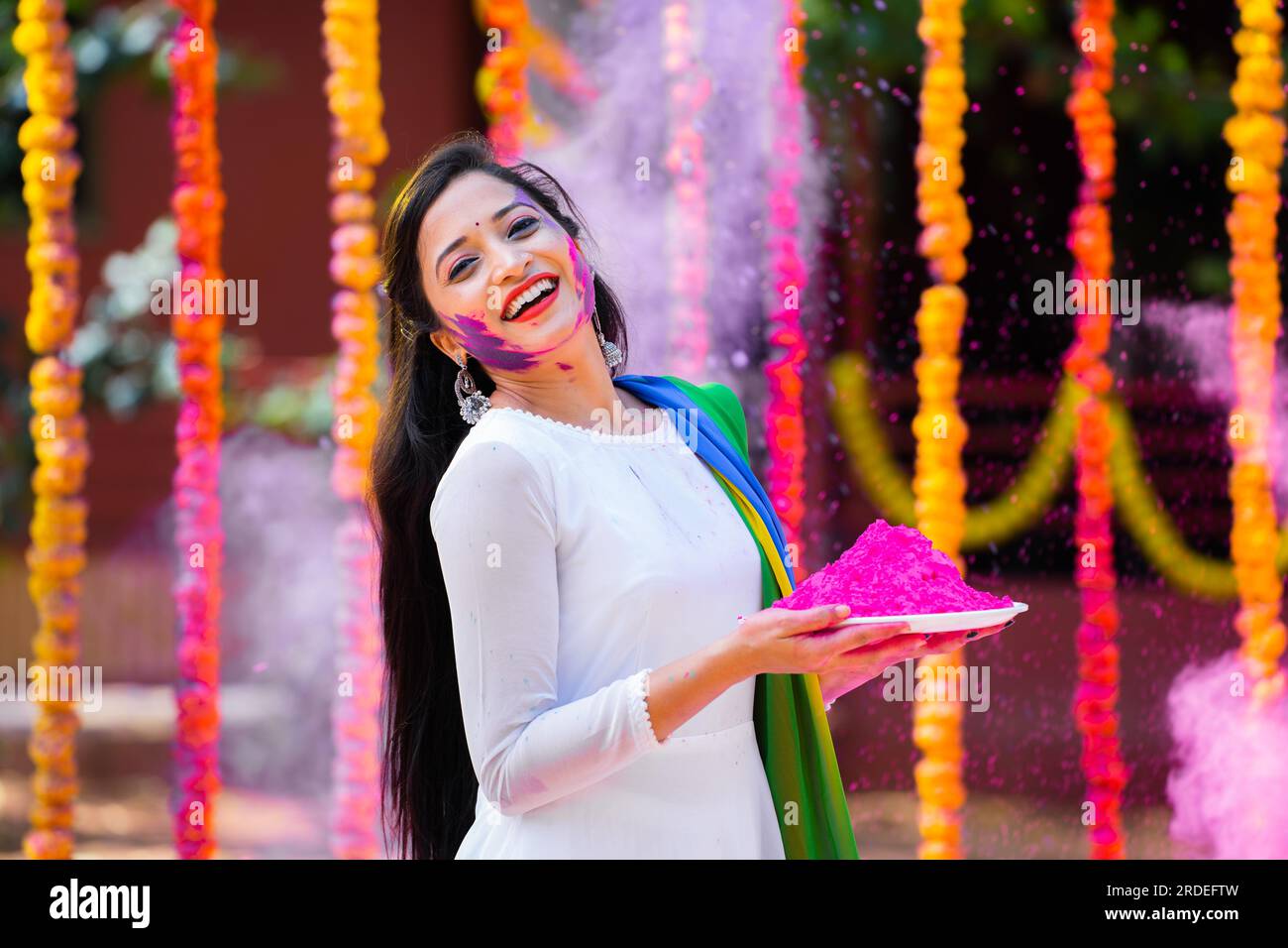 Happy smiling girl with holi color on face by holding holi plate ...