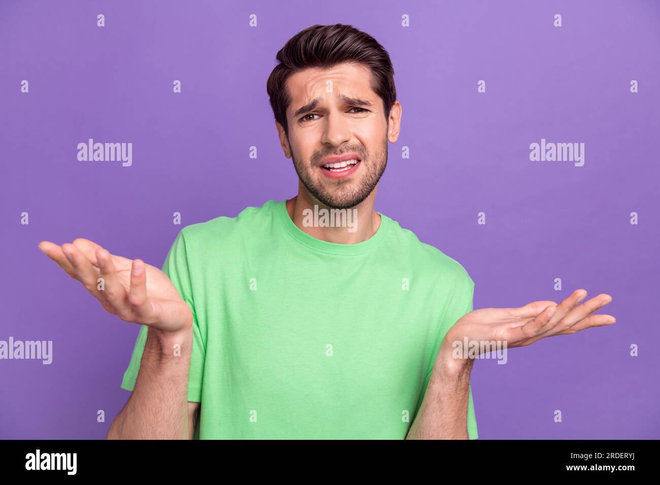 Photo of funny young guy shrug shoulders wearing green t-shirt ...