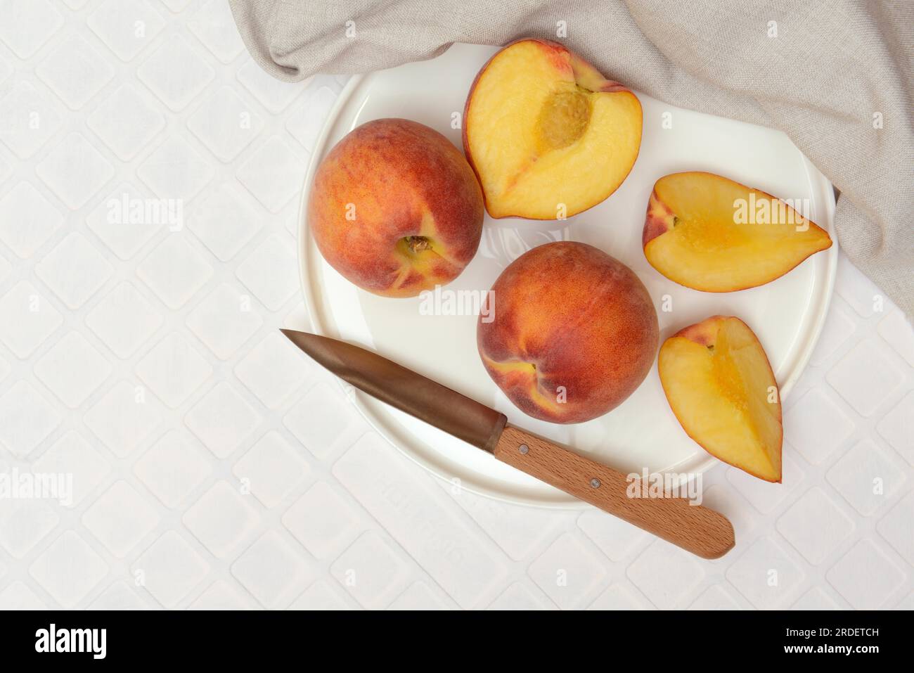 Cut peaches with knife on plate (Prunus persica Stock Photo - Alamy
