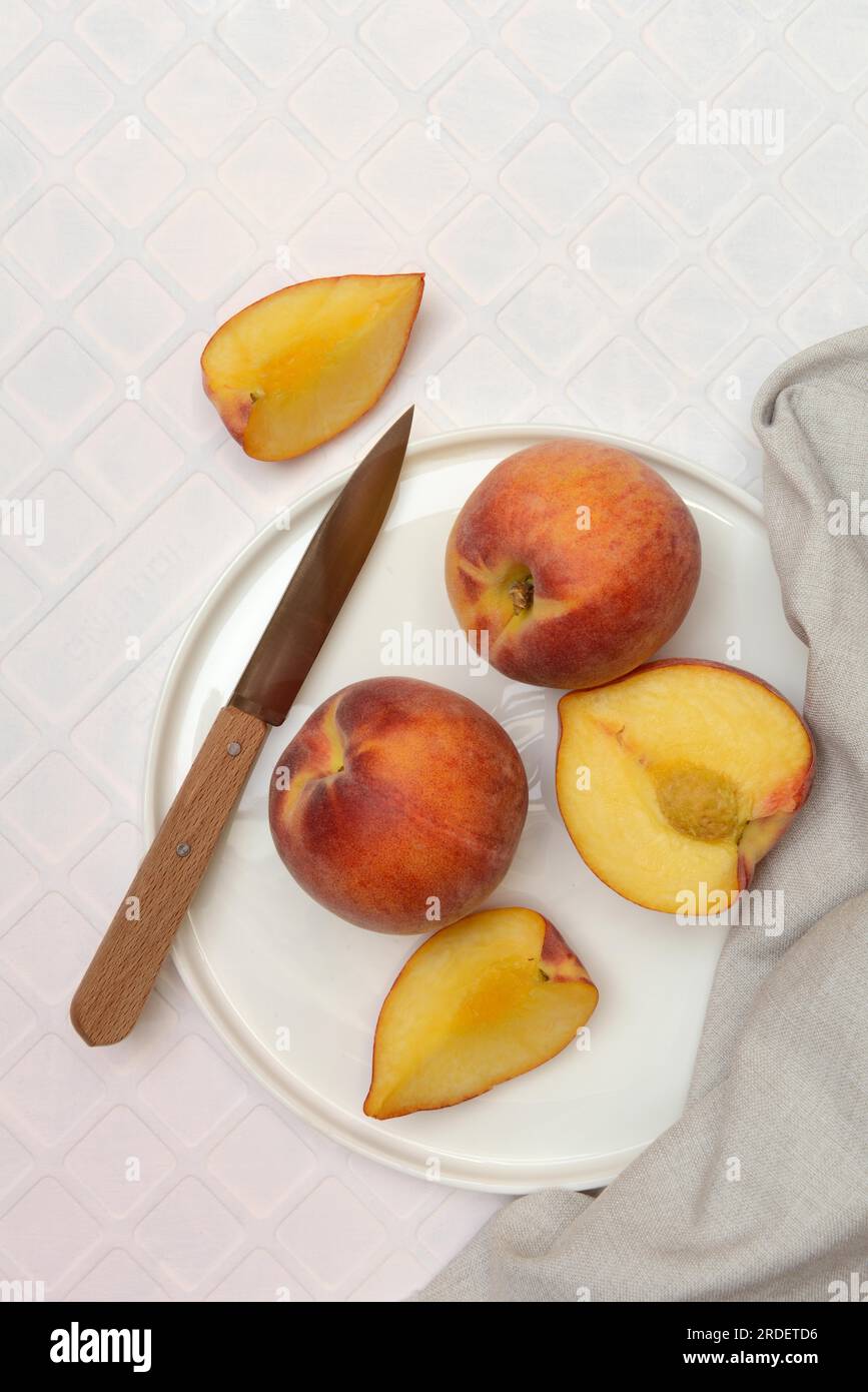Cut peaches with knife on plate (Prunus persica Stock Photo - Alamy