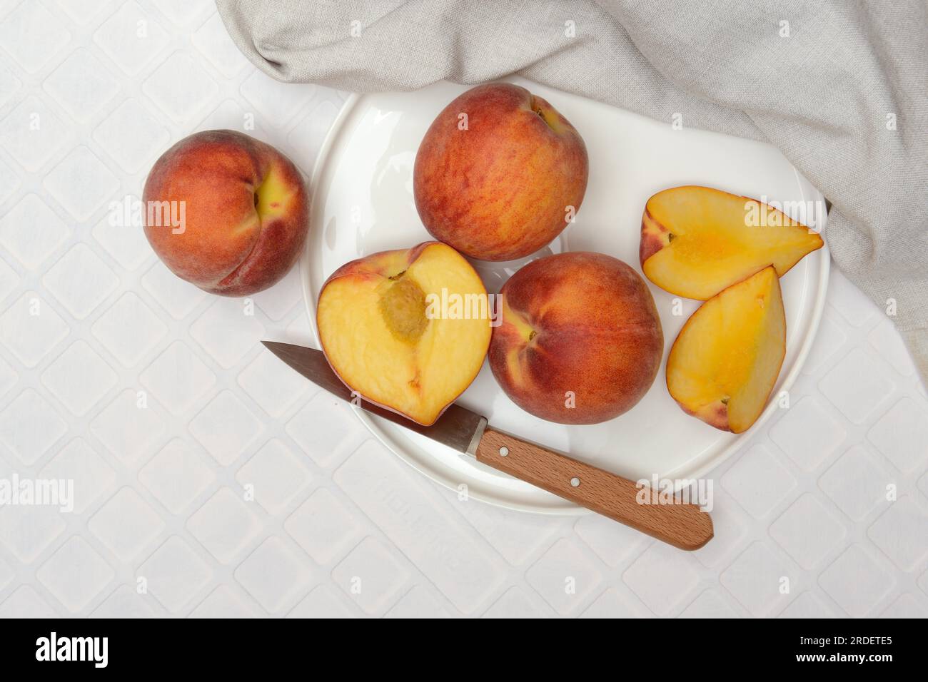 Cut peaches with knife on plate (Prunus persica Stock Photo - Alamy