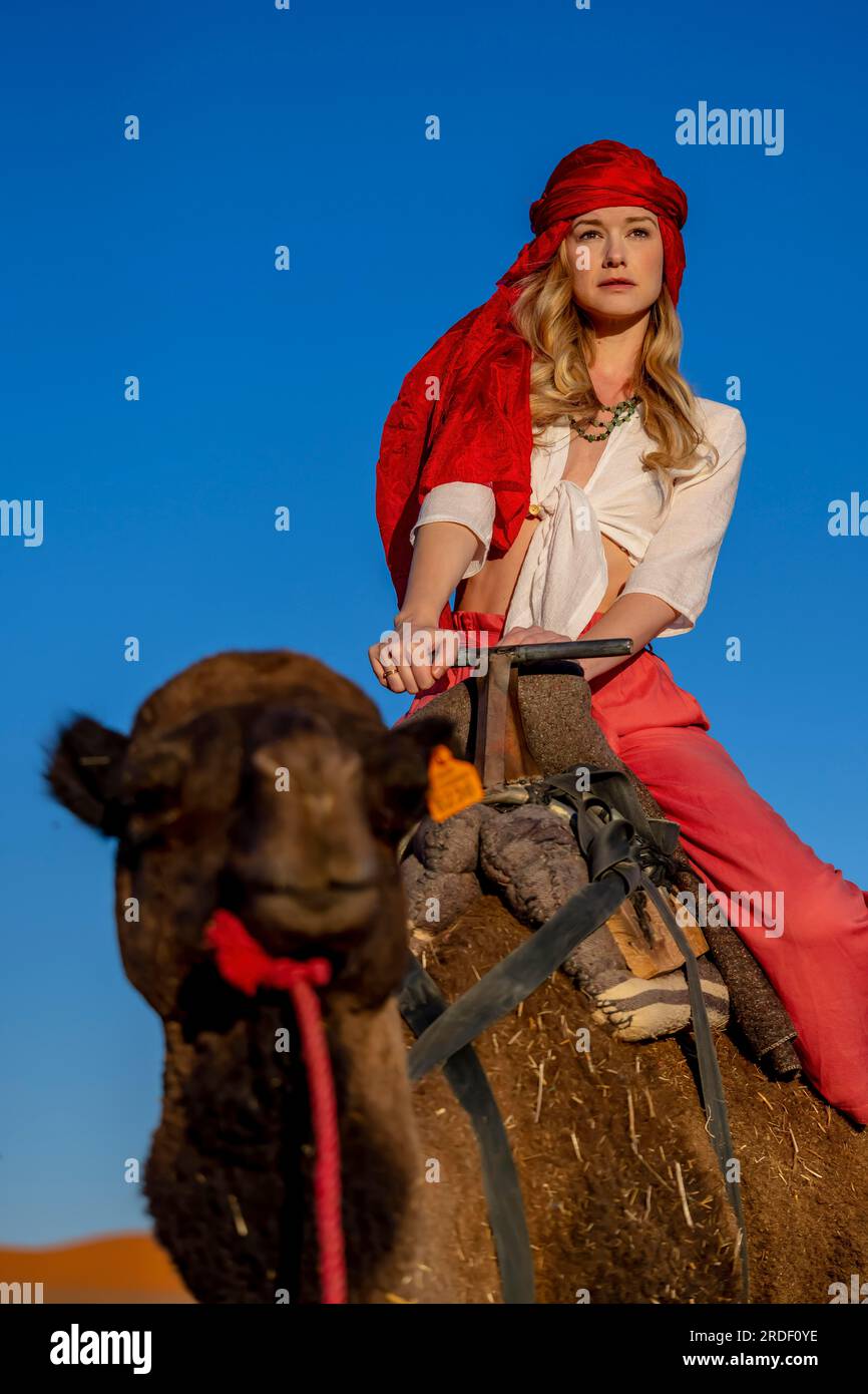 A beautiful model rides a camel through the Saharan Desert in Morocco ...