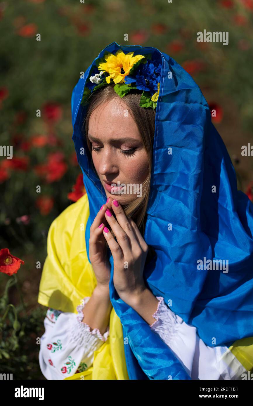 A young blonde Ukrainian woman stands in a field of Red Poppy flowers ...