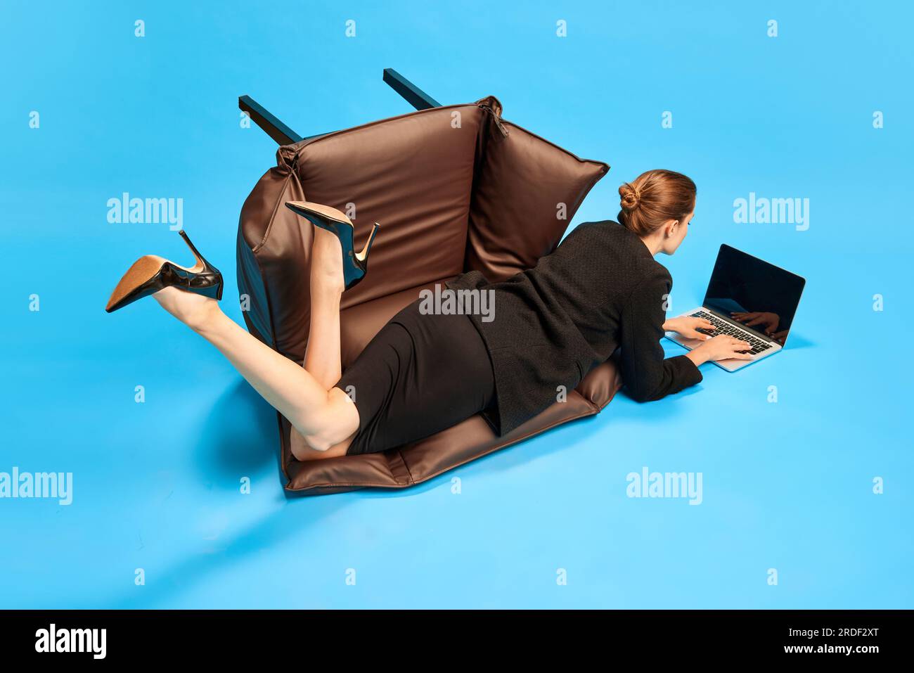 Young woman, employee lying on floor on chair in formal wear and ...