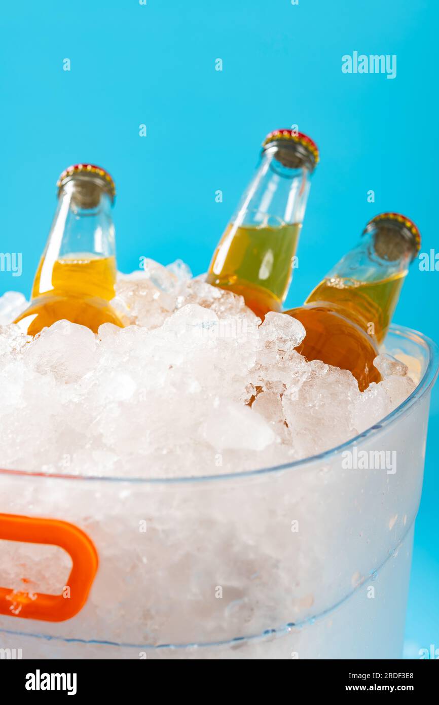 angle view bottles of beer in an iced bucket on blue at vertical ...